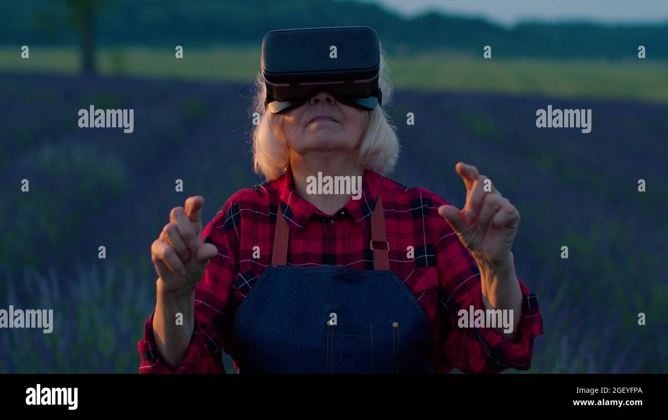 Senior grandmother farmer in virtual reality helmet managing quality in ...