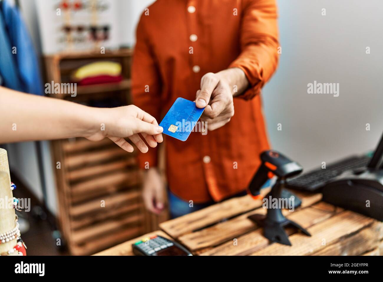 Hand of shopkeeper man giving credit card to customer at clothing store ...
