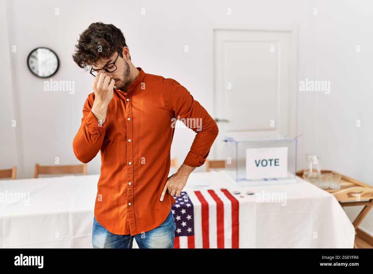 Hispanic man standing by election room tired rubbing nose and eyes ...