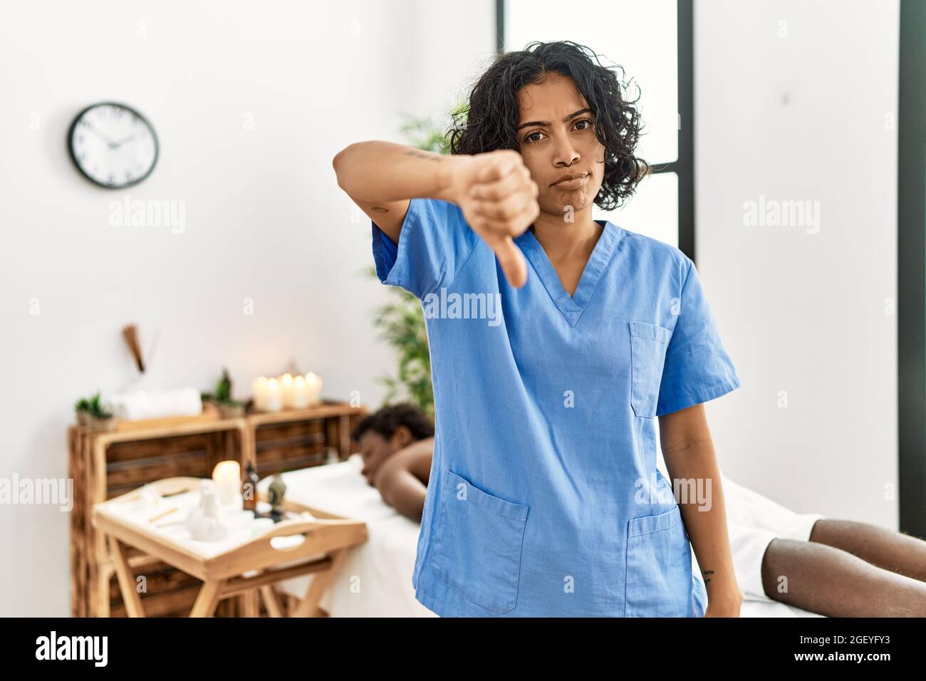 Young therapist woman at wellness spa center looking unhappy and angry ...