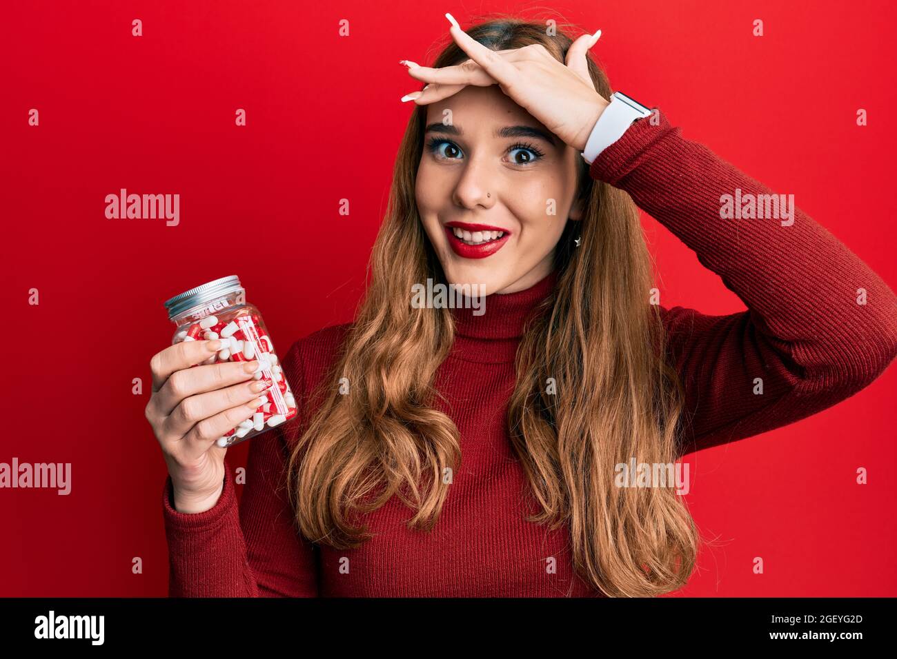 Young blonde woman holding jar of pills stressed and frustrated with ...