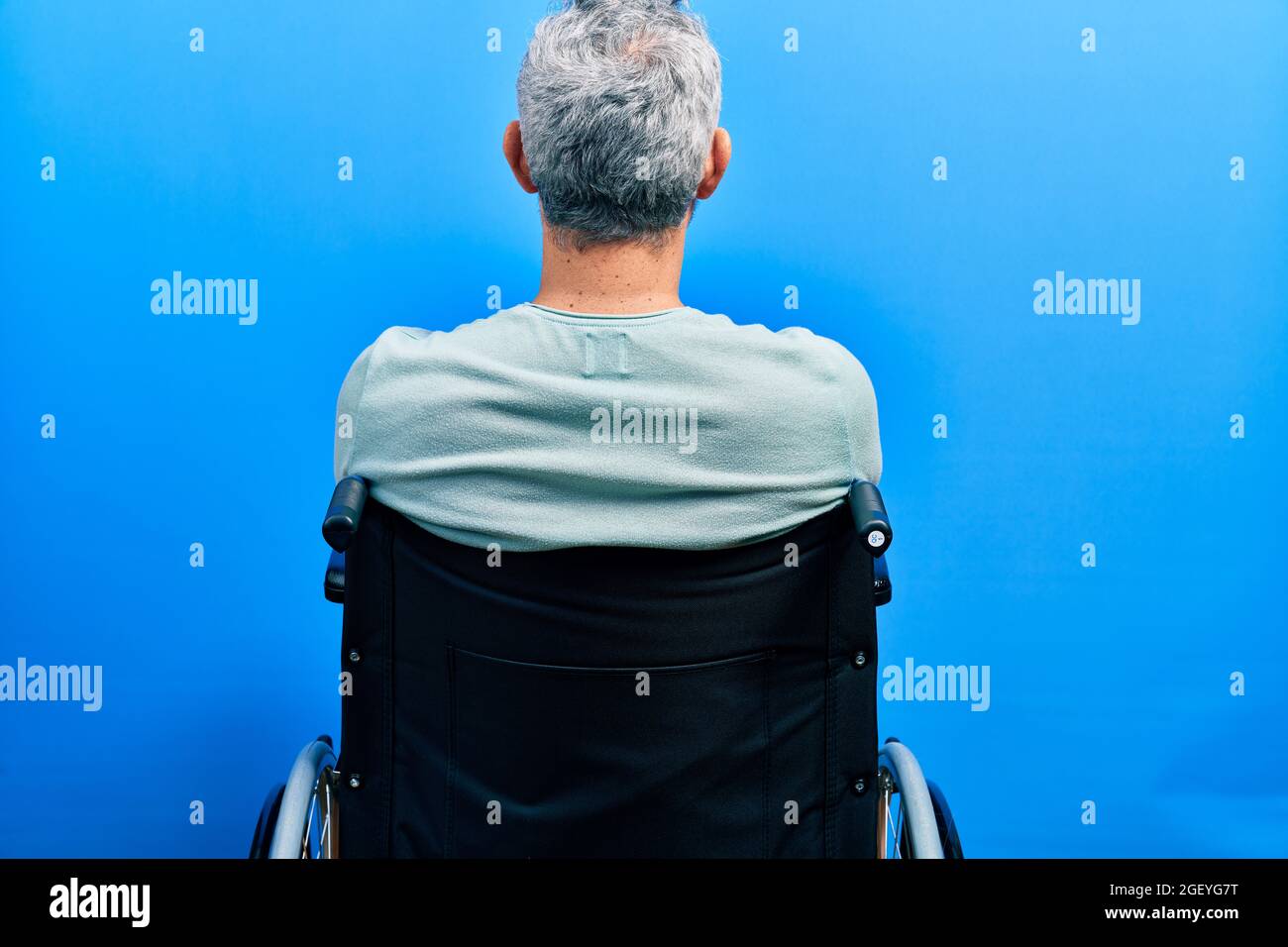 Handsome middle age man with grey hair sitting on wheelchair standing ...