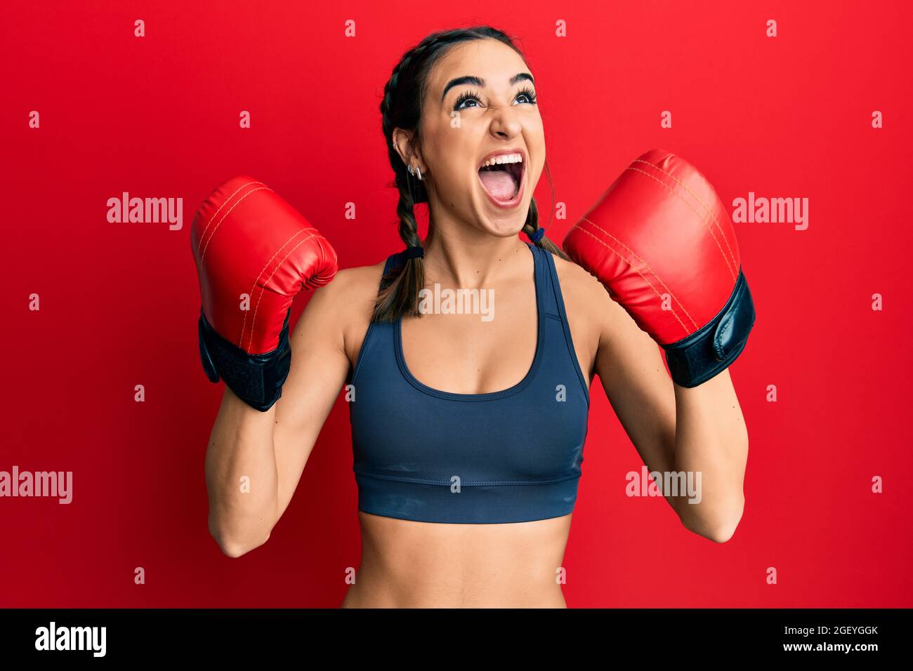 Young brunette girl using boxing gloves wearing braids angry and mad ...