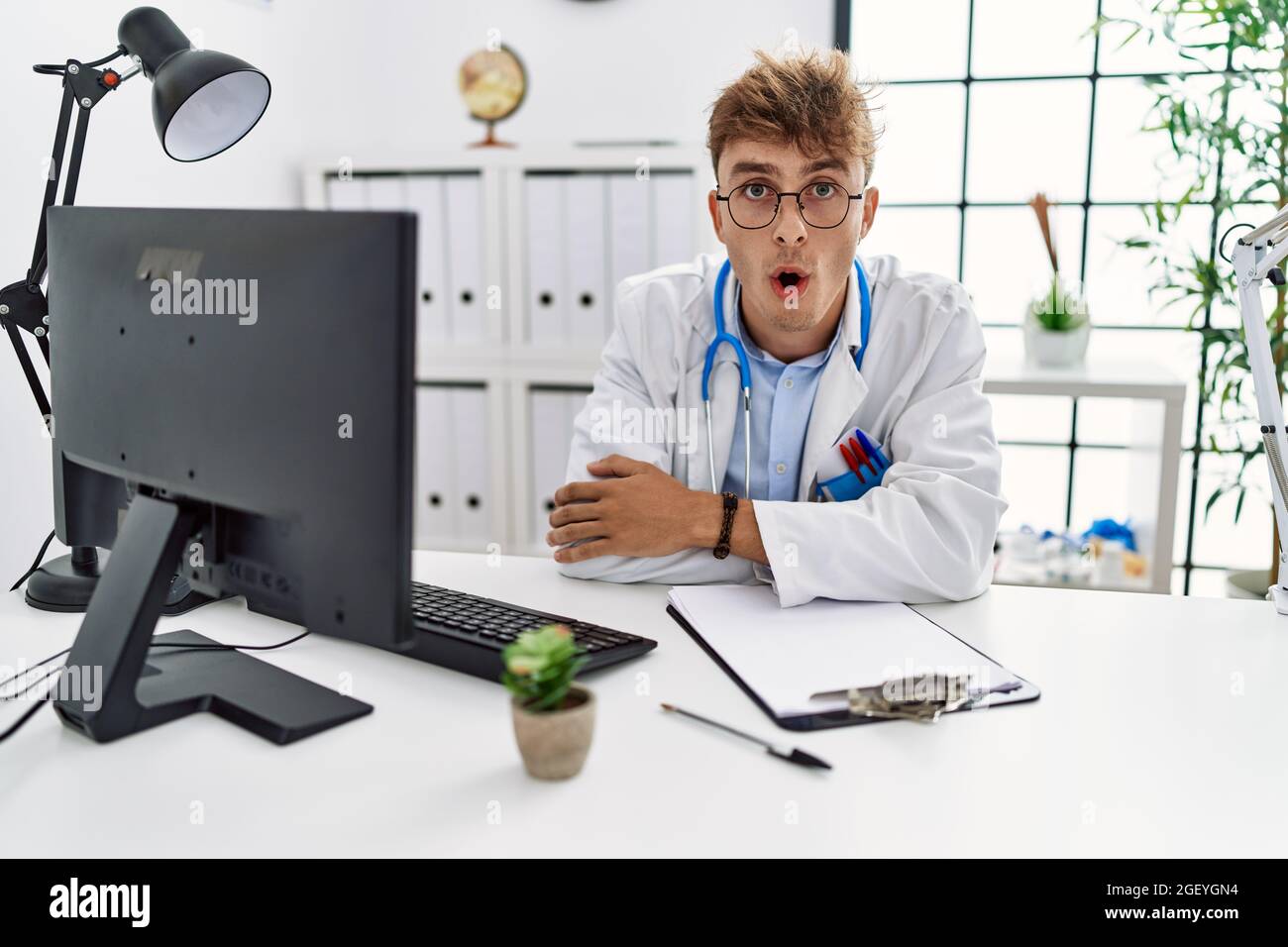 Young caucasian doctor man working at the clinic afraid and shocked ...