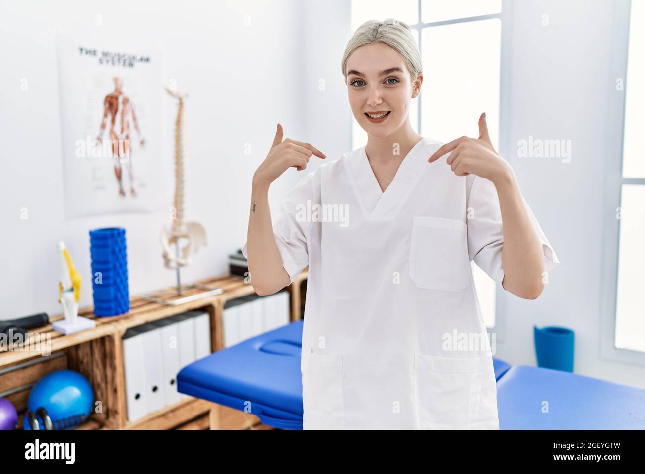 Young caucasian woman working at pain recovery clinic looking confident ...