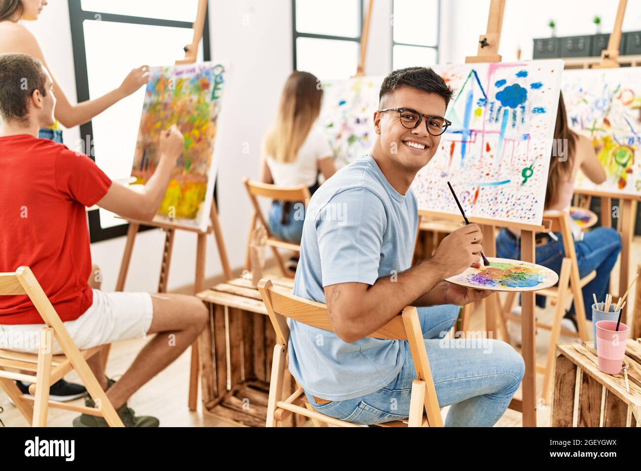 Young man smiling happy drawing with group of people at art studio ...