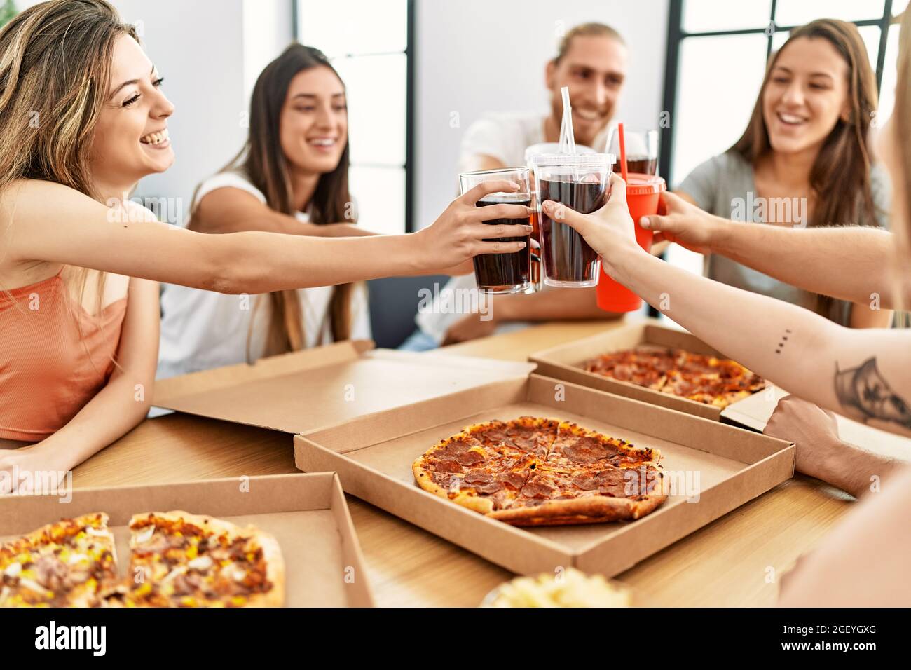 Group of young friends smiling happy eating italian pizza and toasting ...
