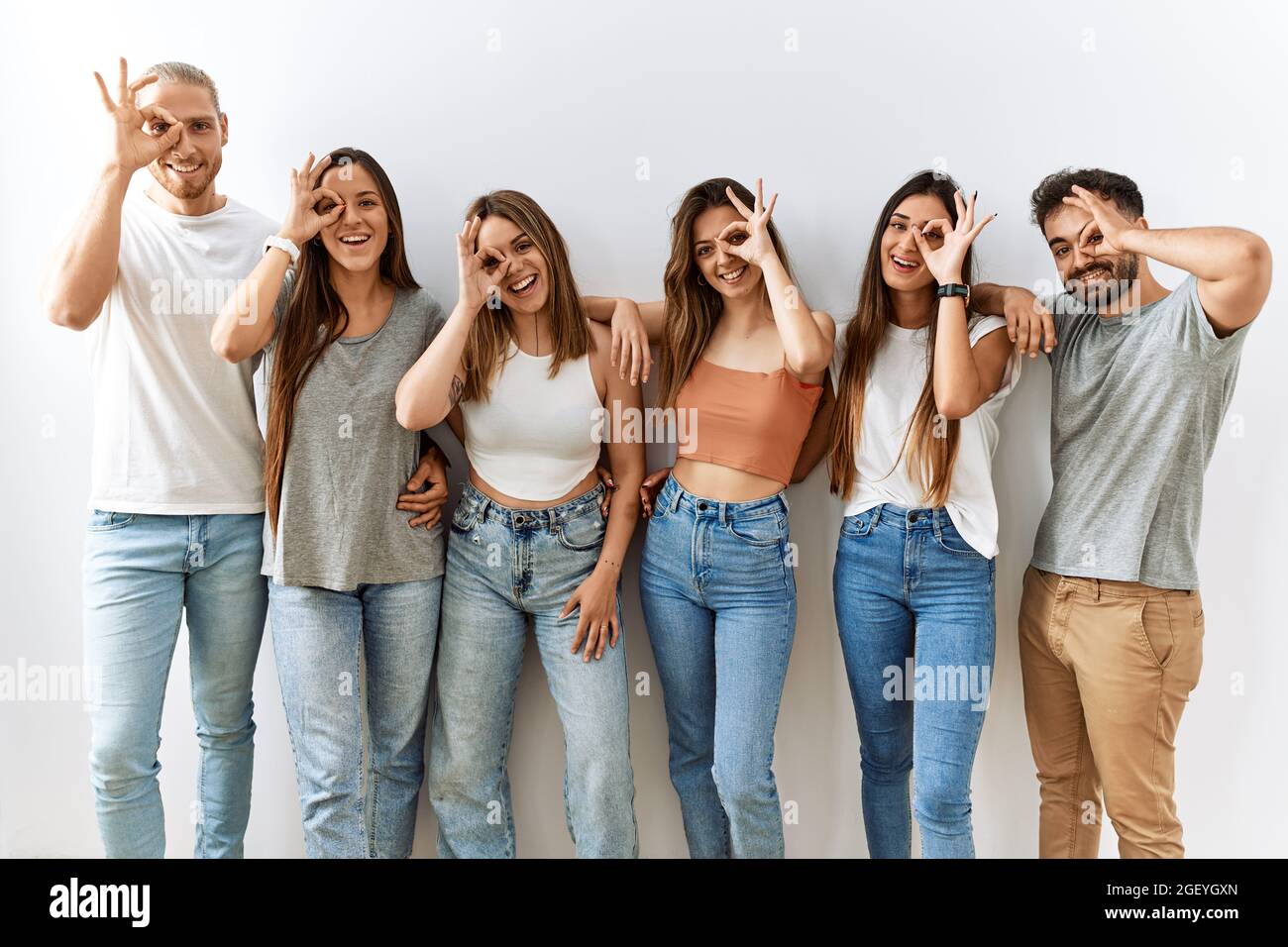 Group of young friends standing together over isolated background doing ...