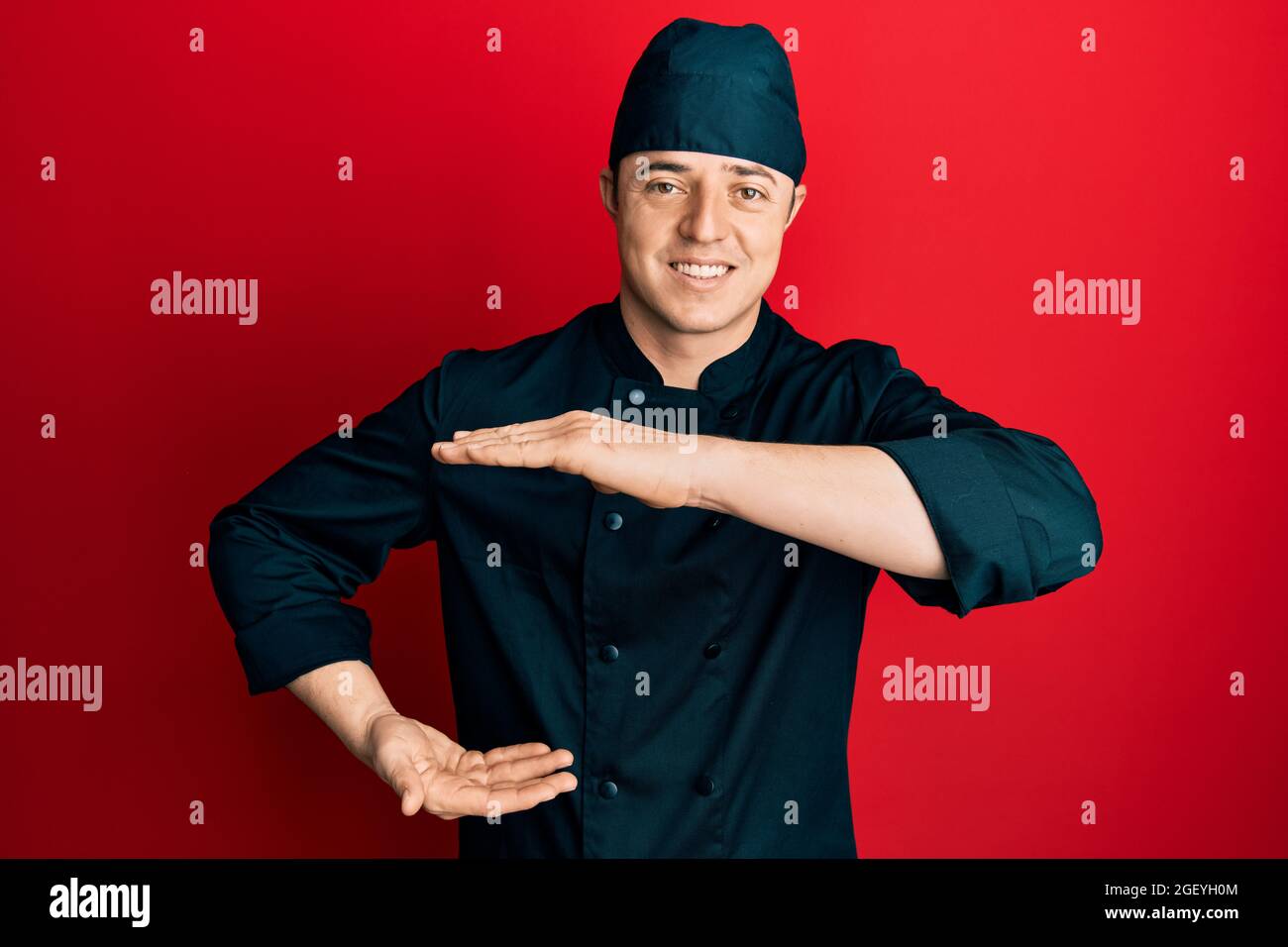 Handsome young man wearing professional cook uniform and hat gesturing ...