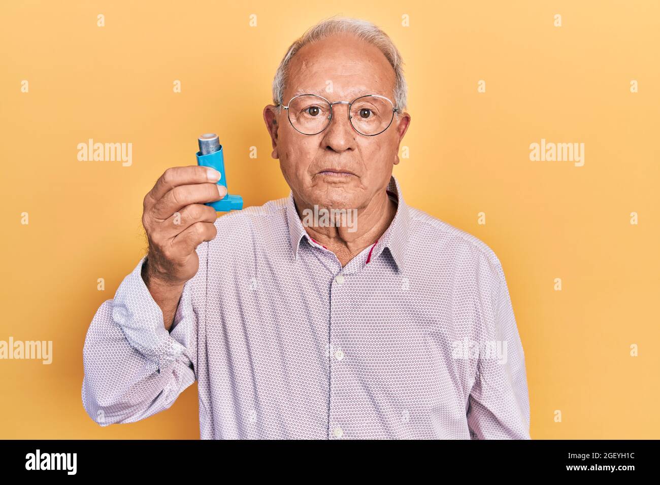 Senior man with grey hair holding medical asthma inhaler thinking ...