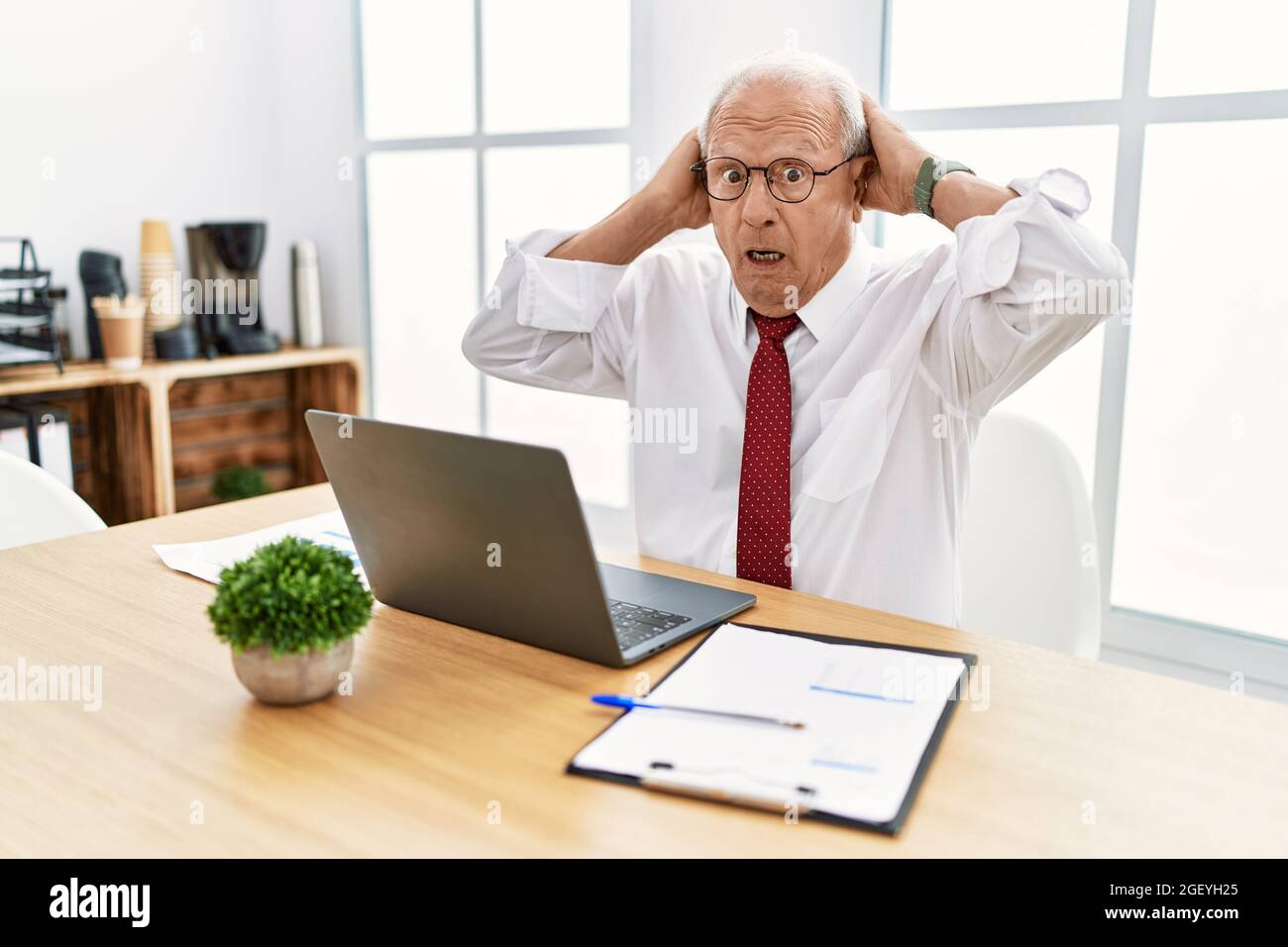 Senior man working at the office using computer laptop crazy and scared ...