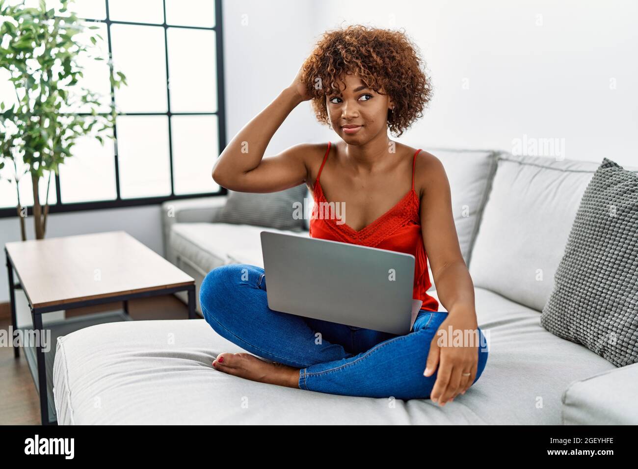 Young african american woman sitting on the sofa at home using laptop ...