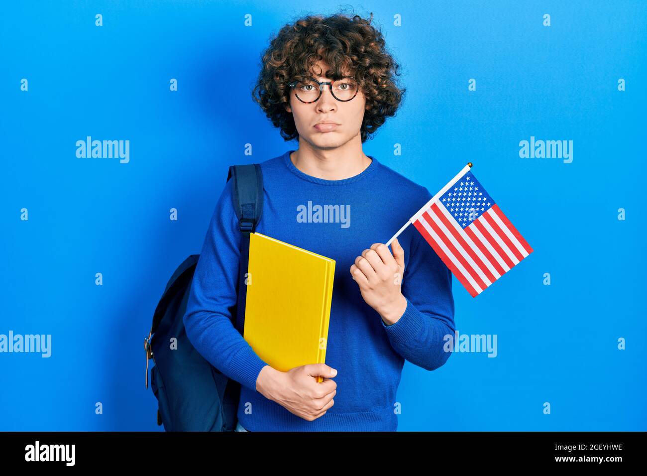 Handsome young man exchange student holding usa flag depressed and ...