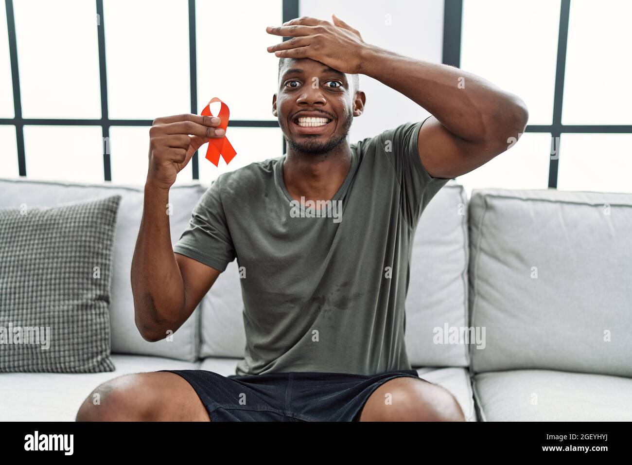 Young african american man holding support red ribbon sitting on the ...