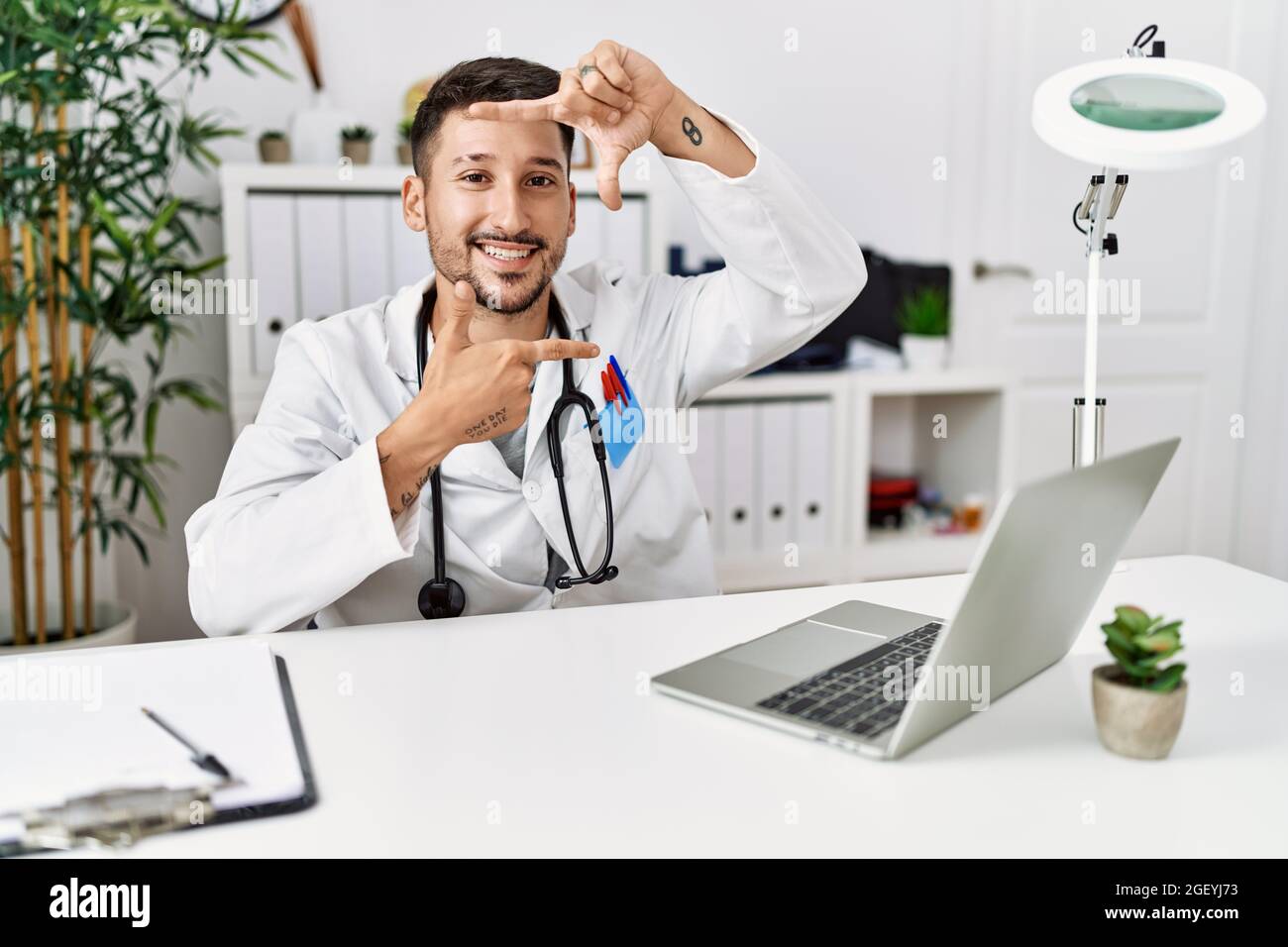 Young doctor working at the clinic using computer laptop smiling making ...