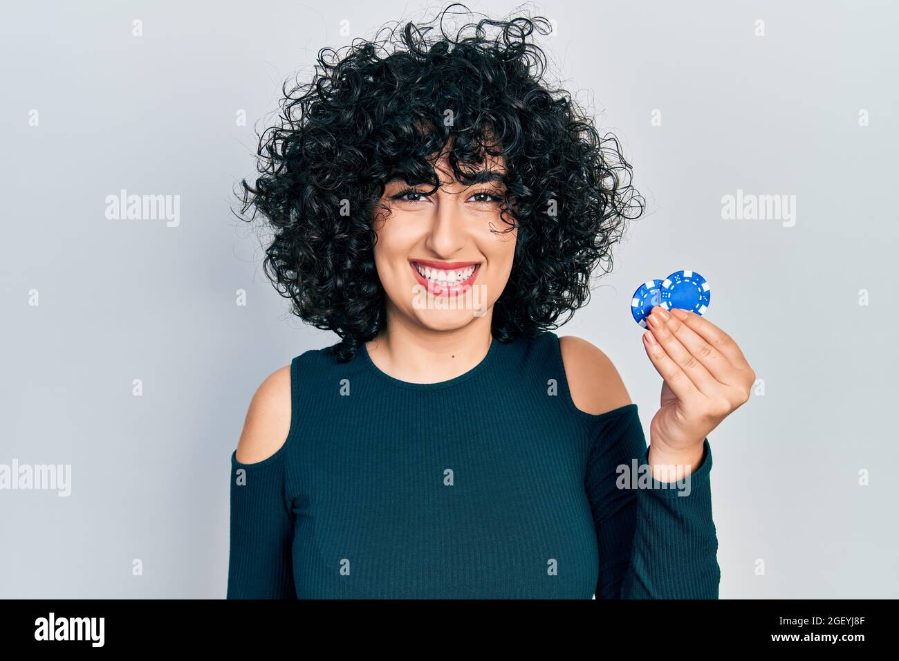 Young middle east woman playing poker holding casino chips looking ...