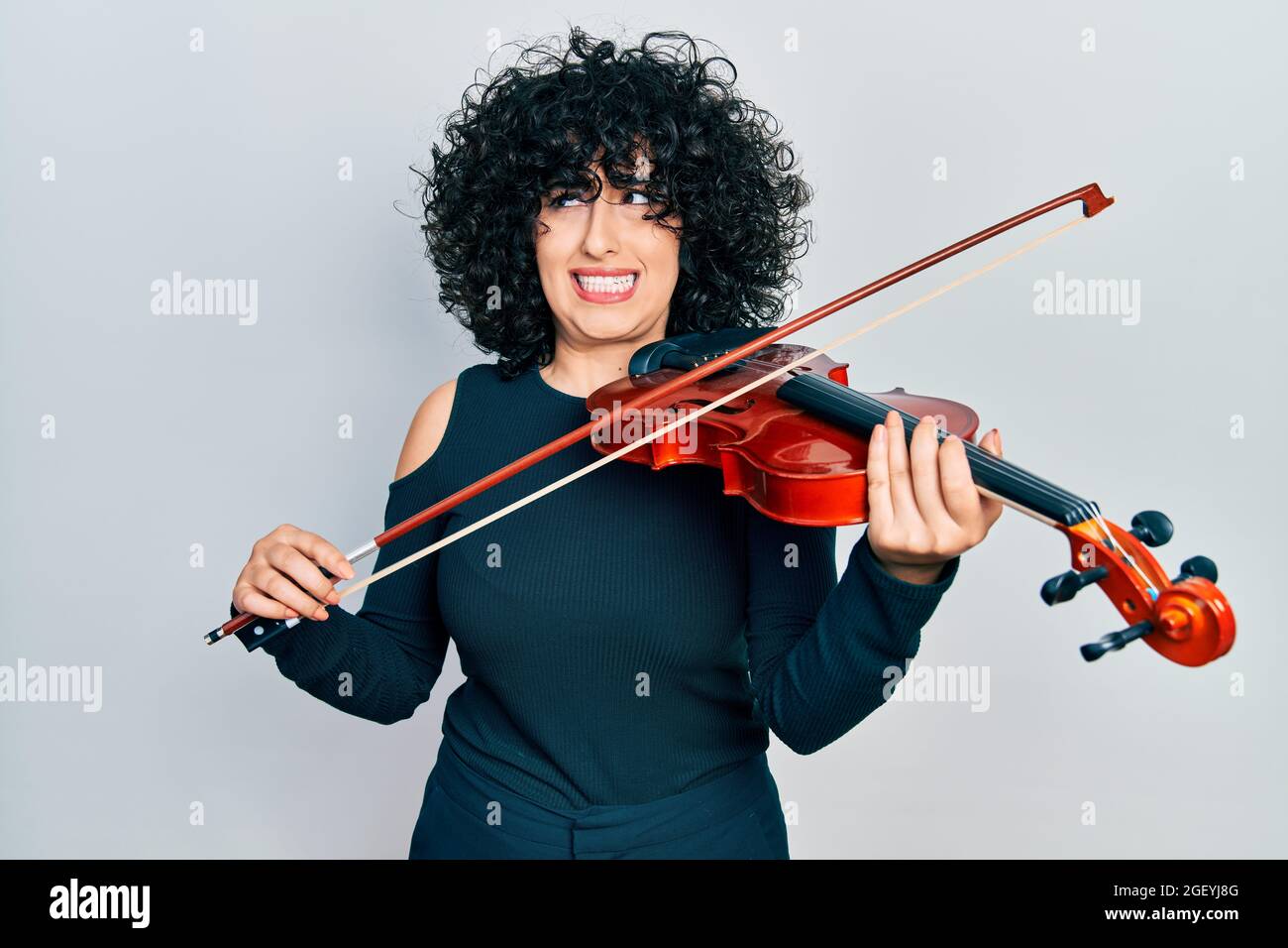 Young middle east woman playing violin angry and mad screaming ...