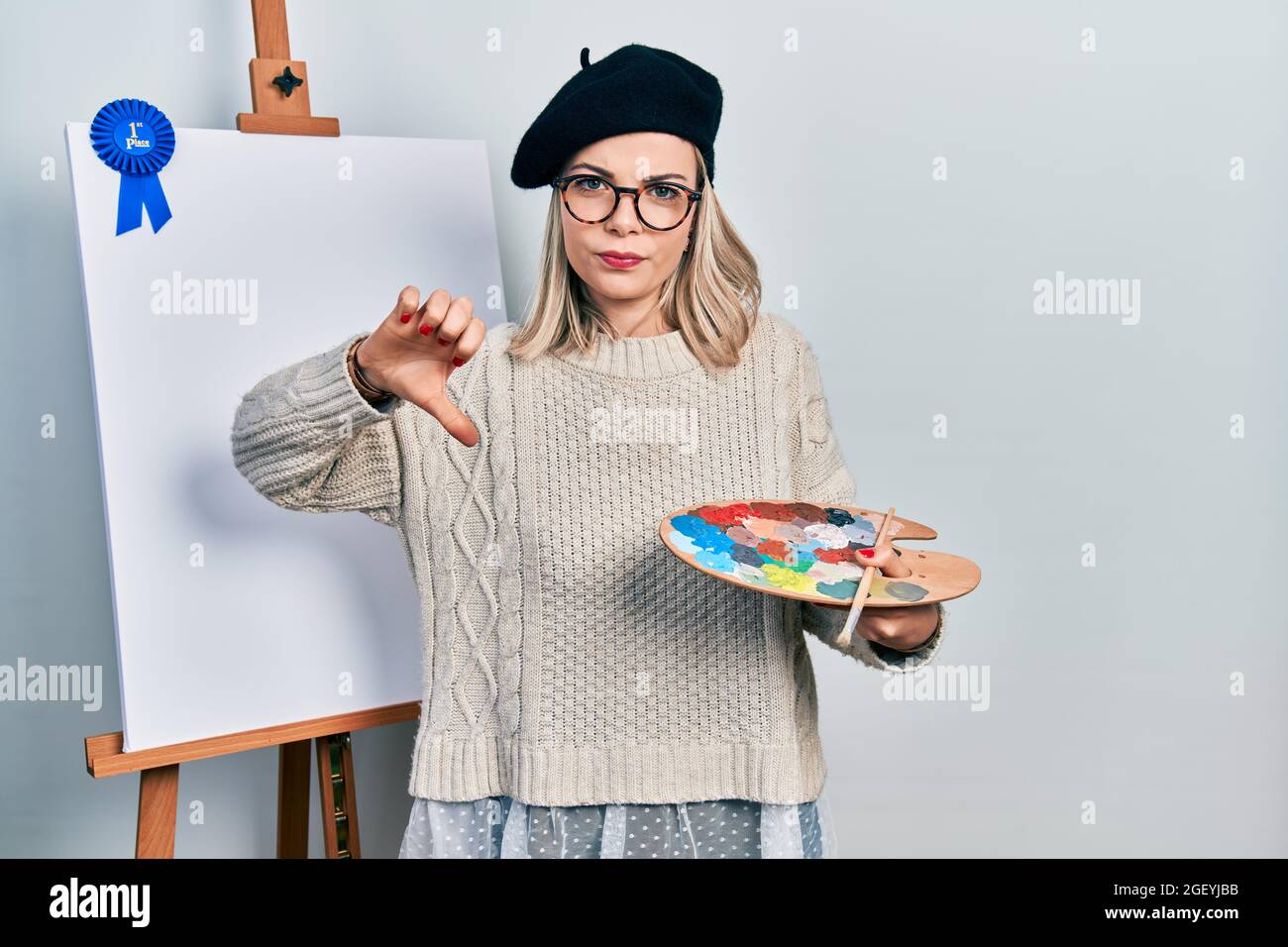 Beautiful caucasian woman drawing with palette on easel stand winner ...