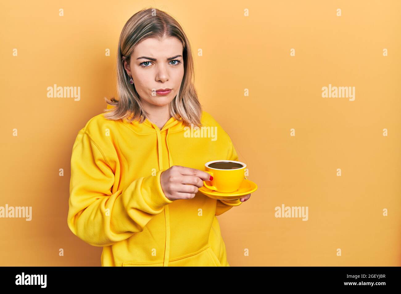 Beautiful caucasian woman drinking a cup coffee skeptic and nervous ...