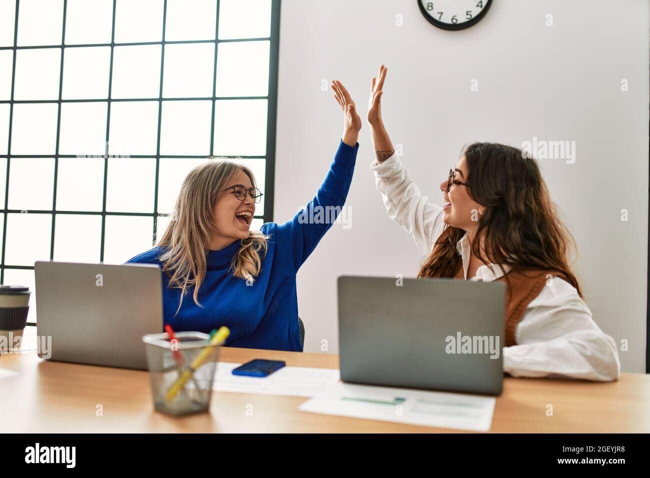 Two business worker woman raised up hands hitting five at the office ...