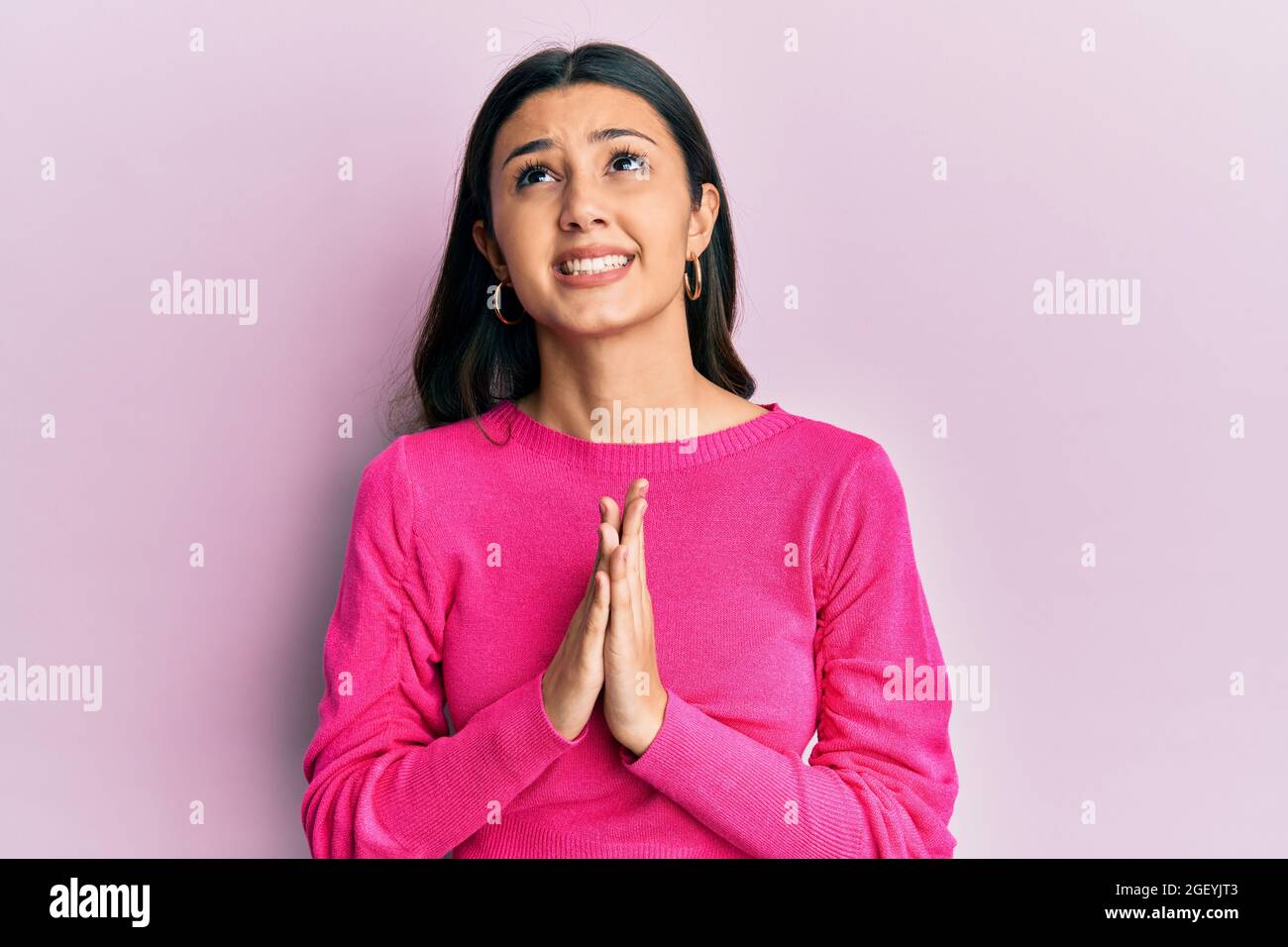 Young hispanic woman wearing casual clothes begging and praying with ...