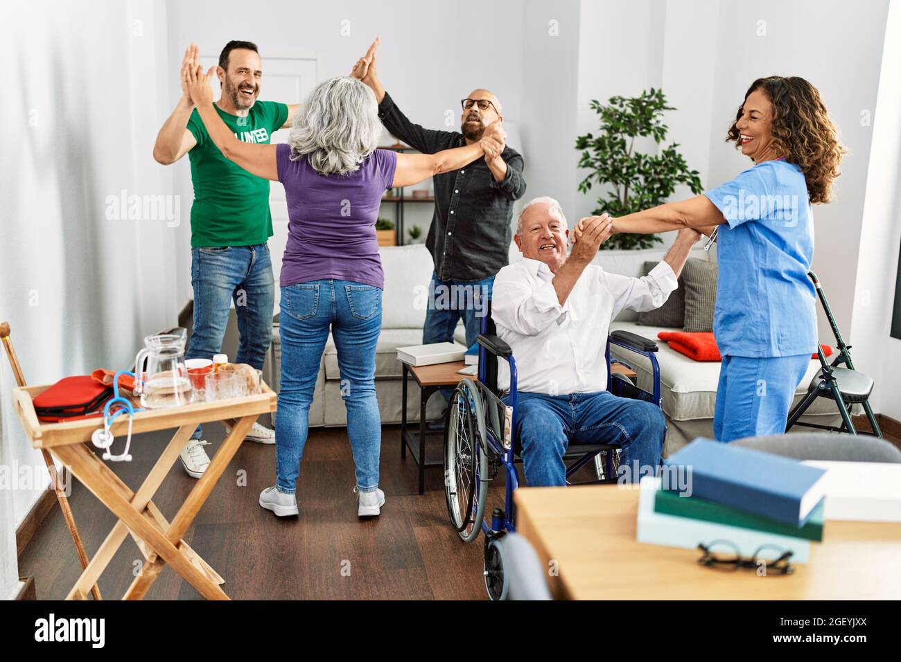 Group of retired people having party dancing with doctor and volunteer ...