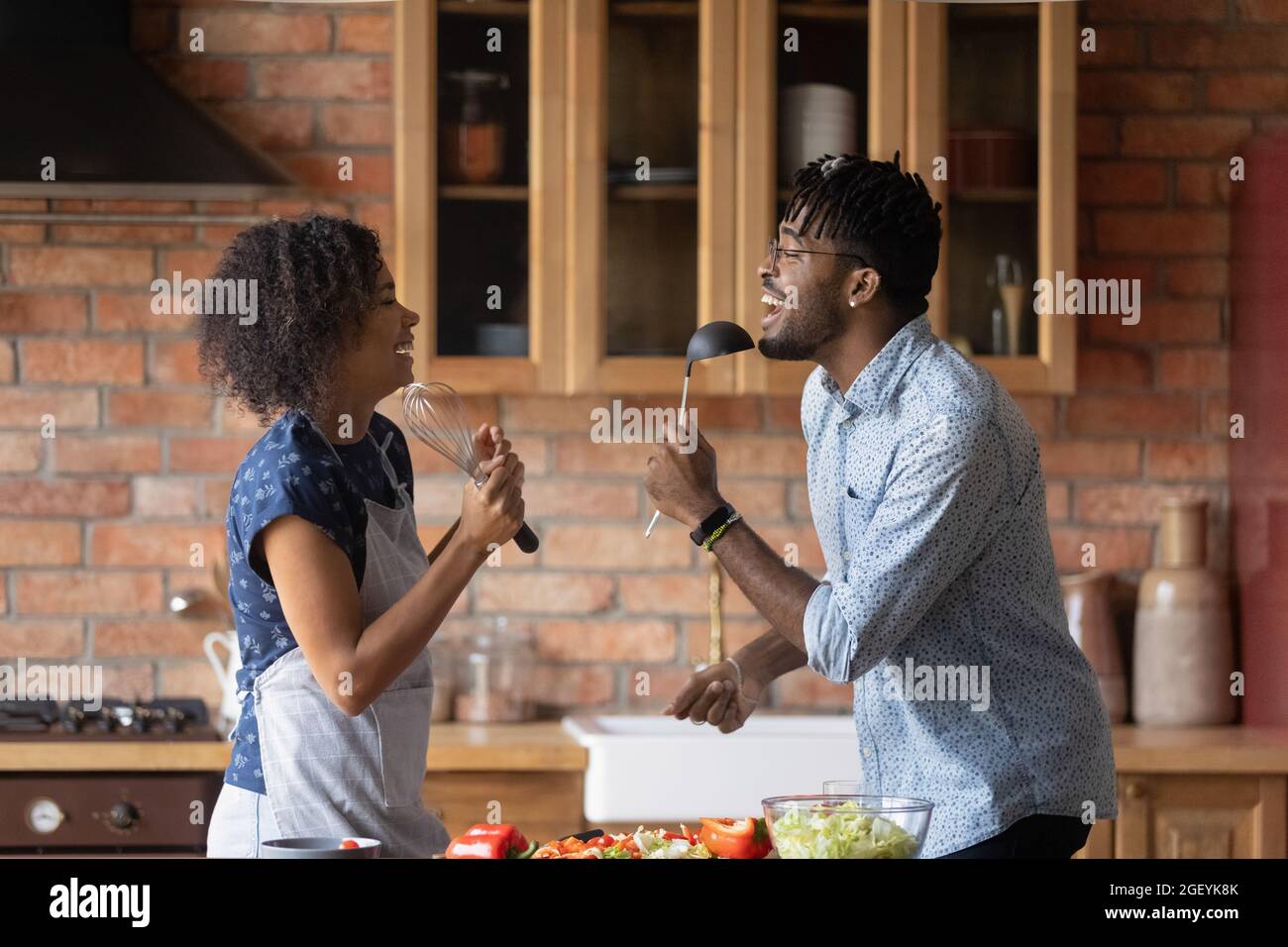 Happy excited African couple singing songs at whisk and ladle Stock ...
