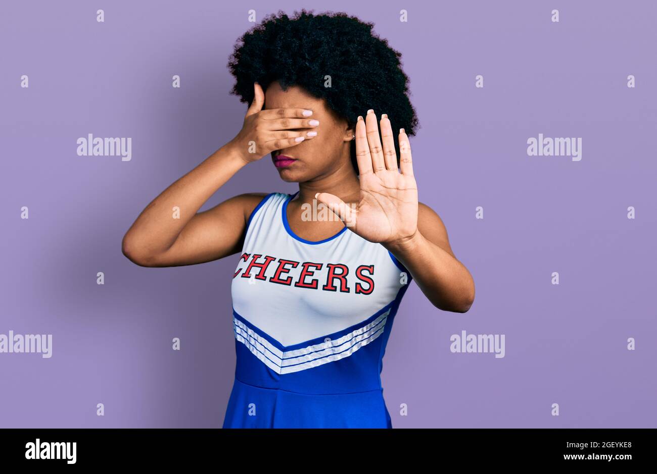 Young african american woman wearing cheerleader uniform covering eyes ...