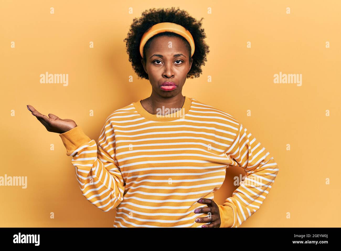 Young african american woman presenting with open palms, holding ...