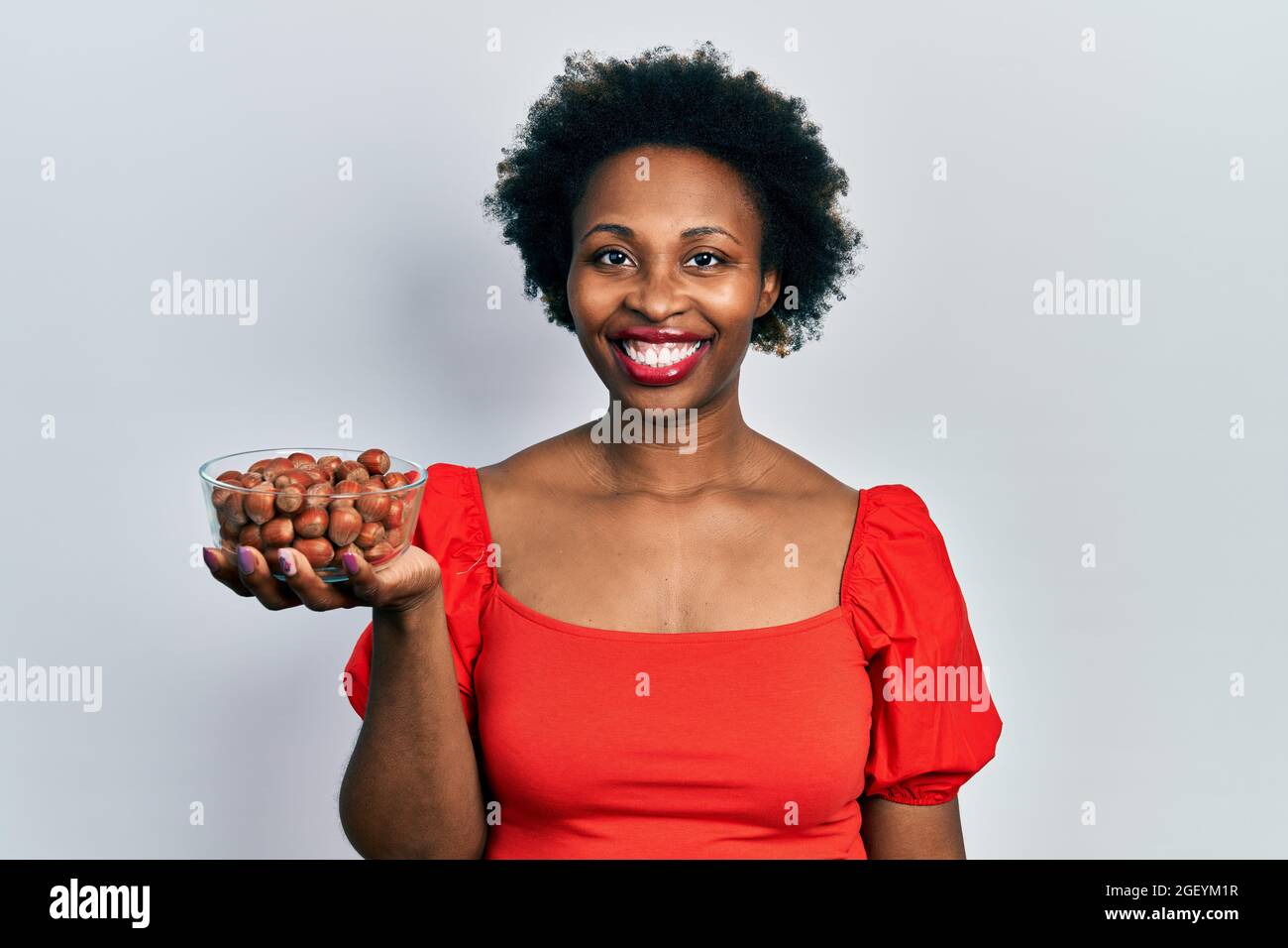 Young african american woman holding raw hazelnuts looking positive and ...