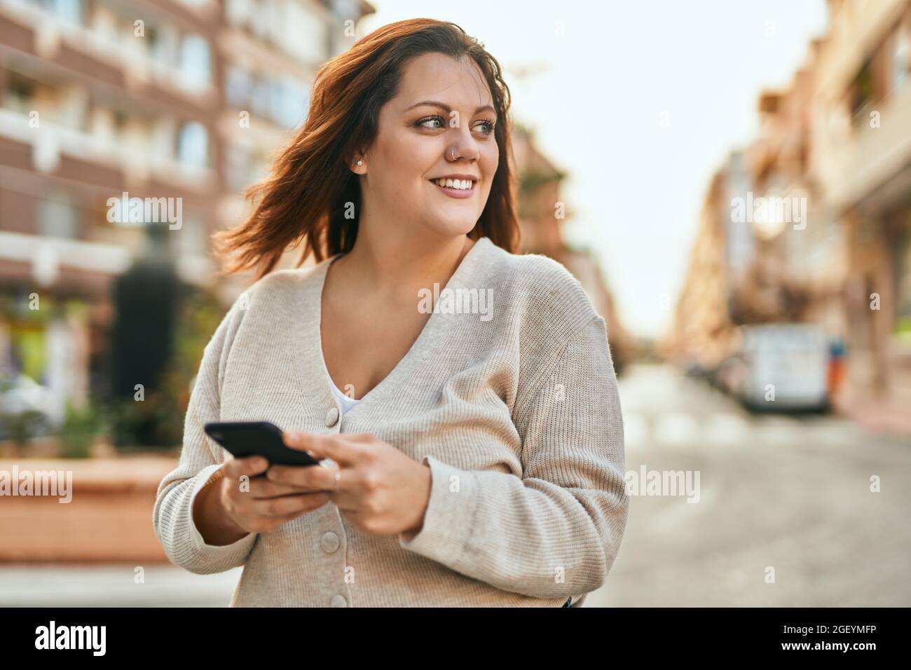 Young irish plus size girl smiling happy using smartphone at the city ...