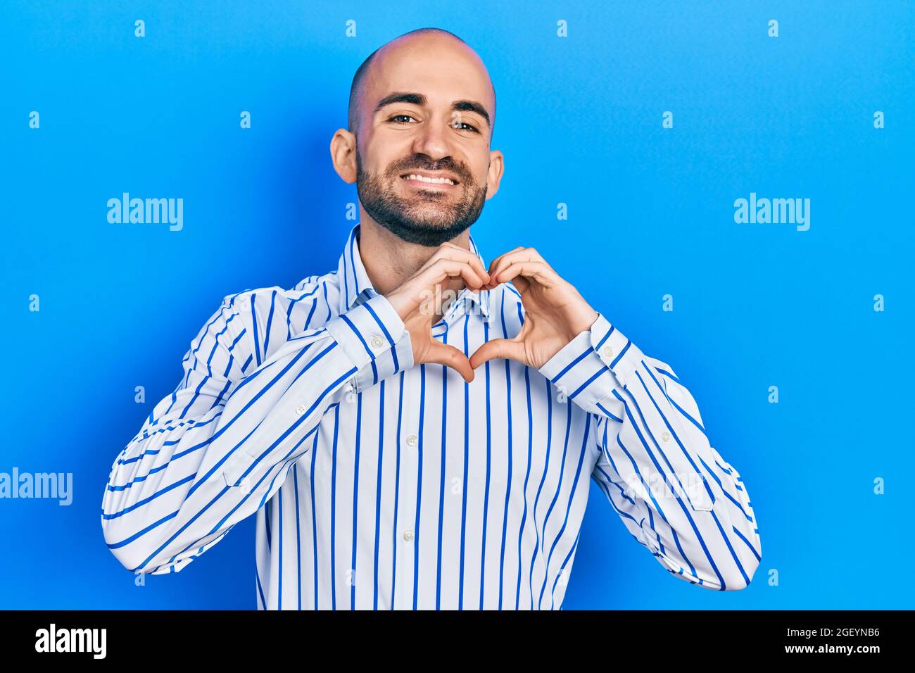 Young bald man wearing elegant clothes smiling in love doing heart ...