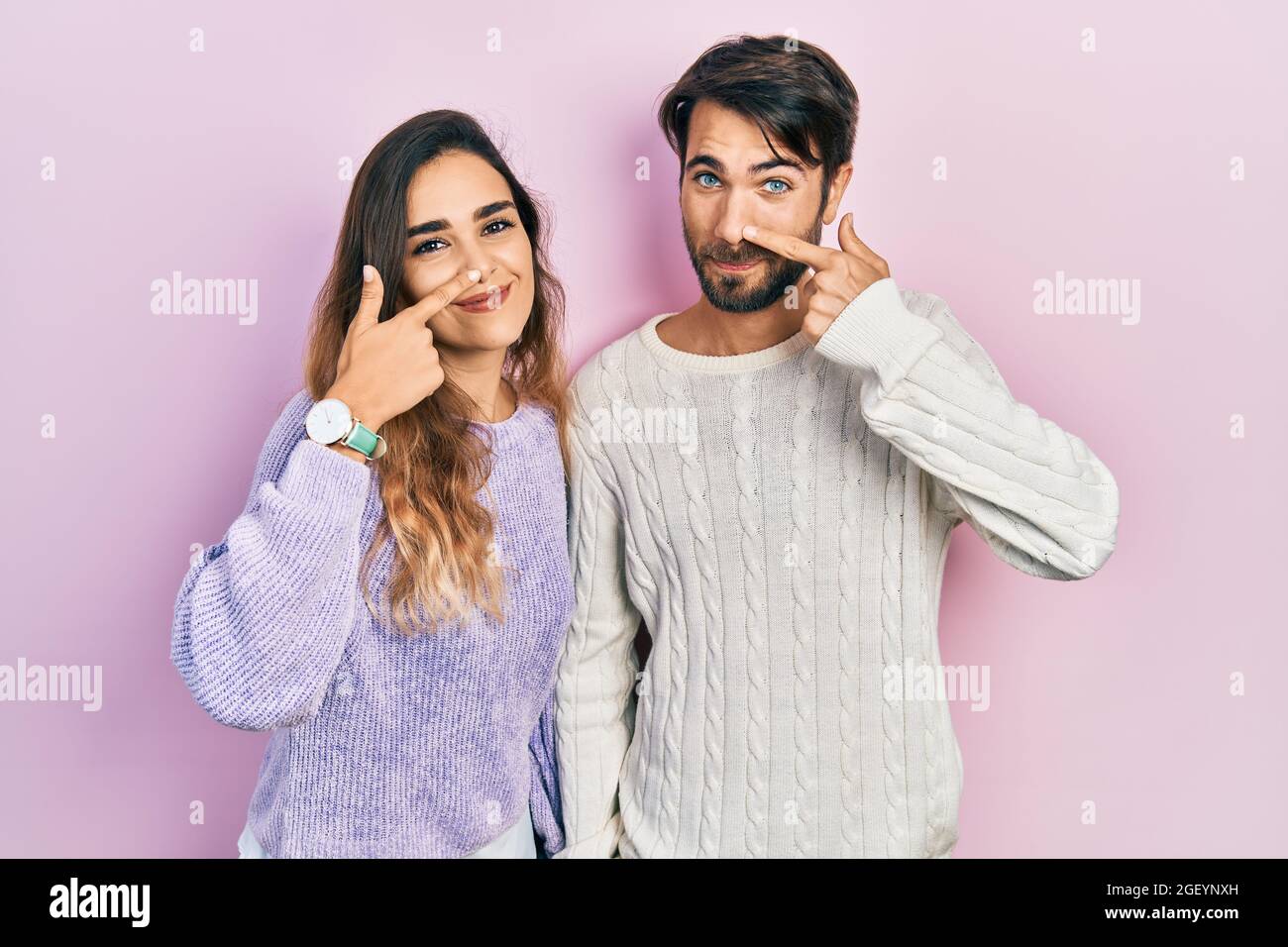 Young hispanic couple wearing casual clothes pointing with hand finger ...