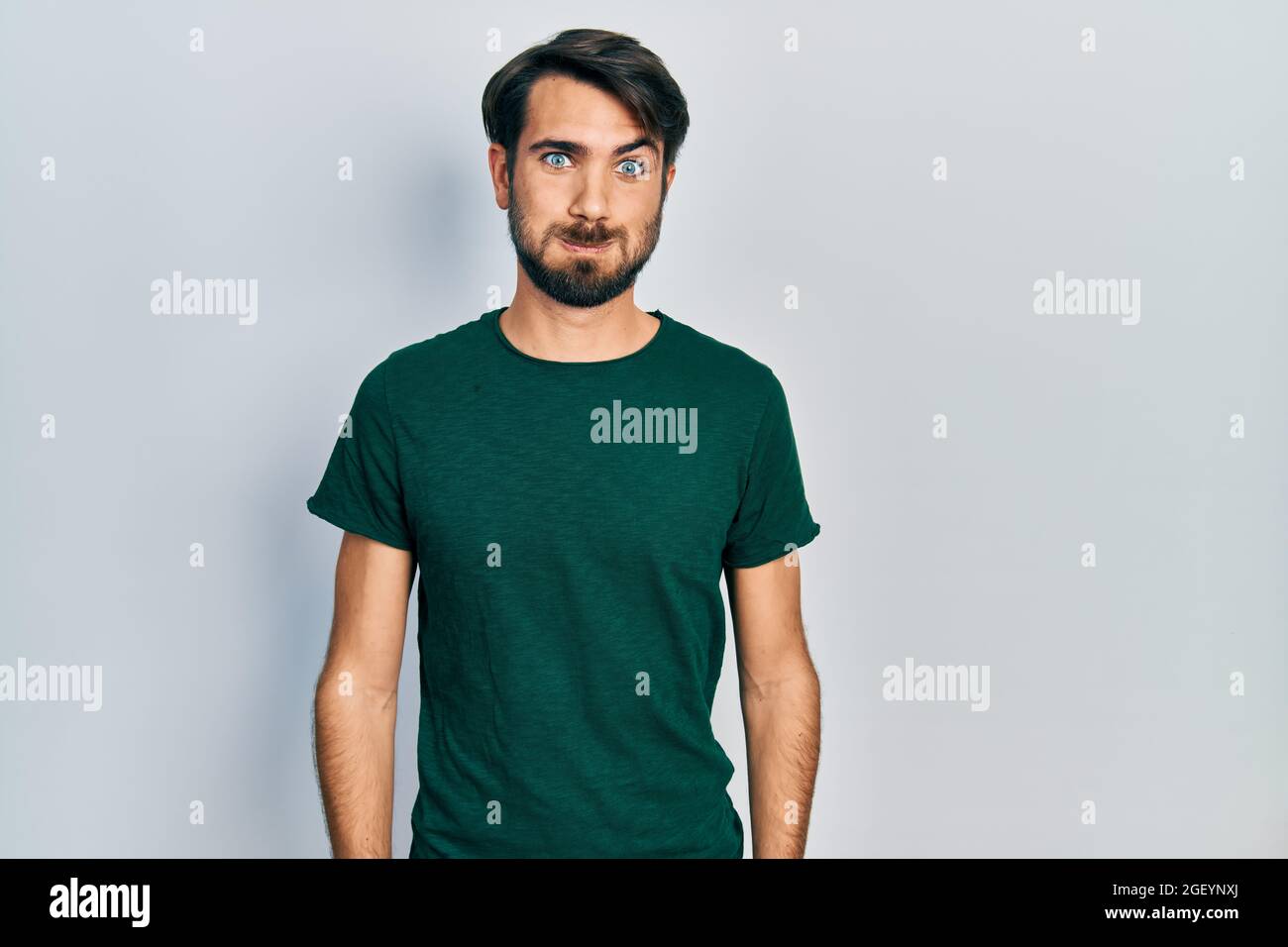 Young hispanic man wearing casual white tshirt puffing cheeks with ...