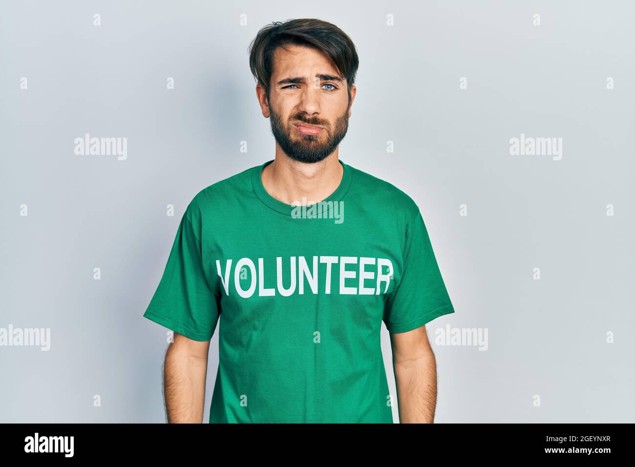 Young hispanic man wearing volunteer t shirt depressed and worry for ...