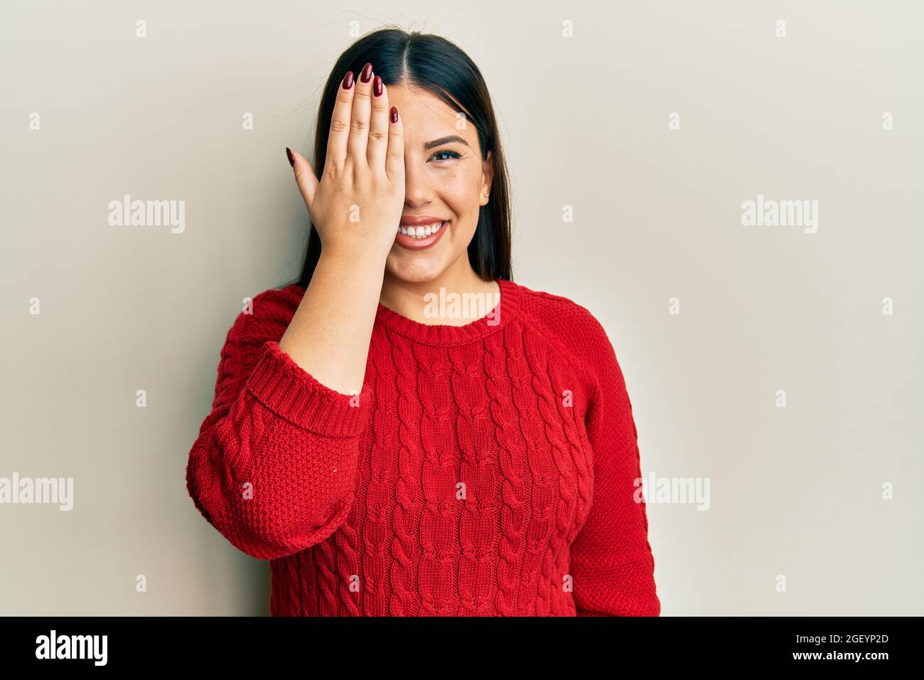 Beautiful brunette woman wearing wool winter sweater covering one eye ...