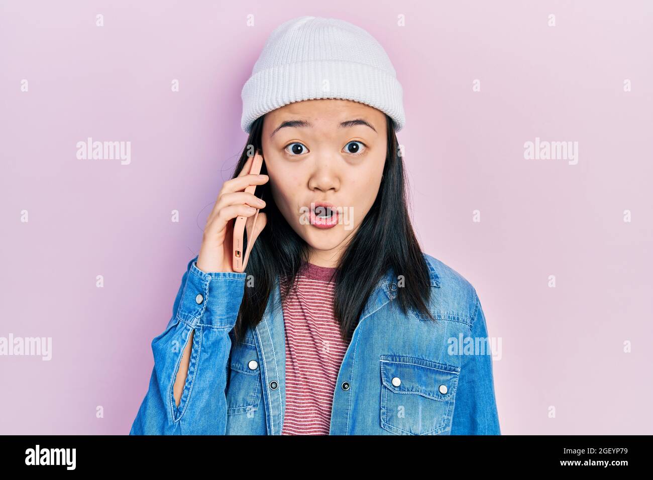 Young chinese girl having conversation talking on the smartphone scared ...