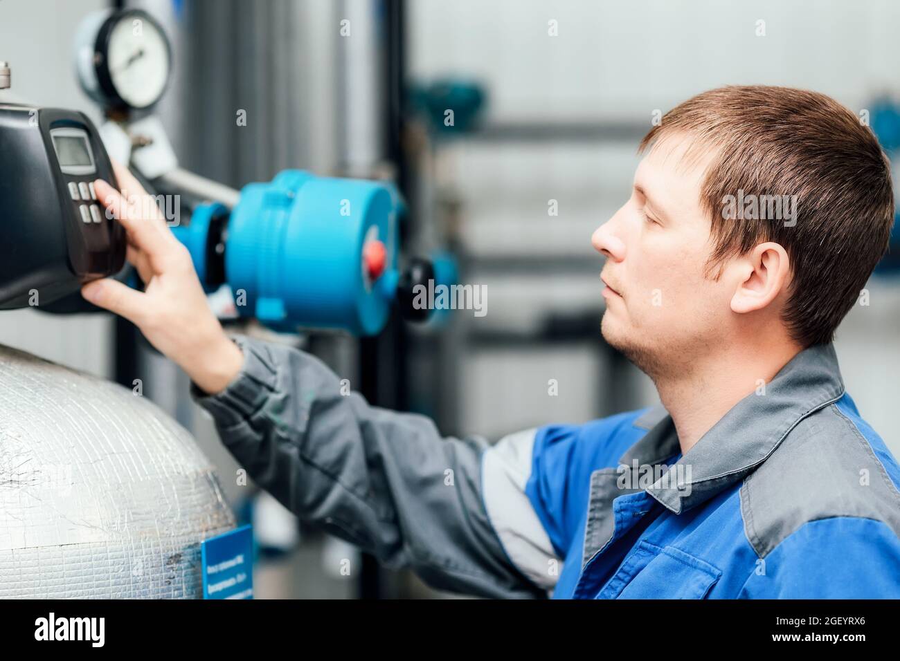 A man in work clothes checks the sensors of the boiler or compressor ...