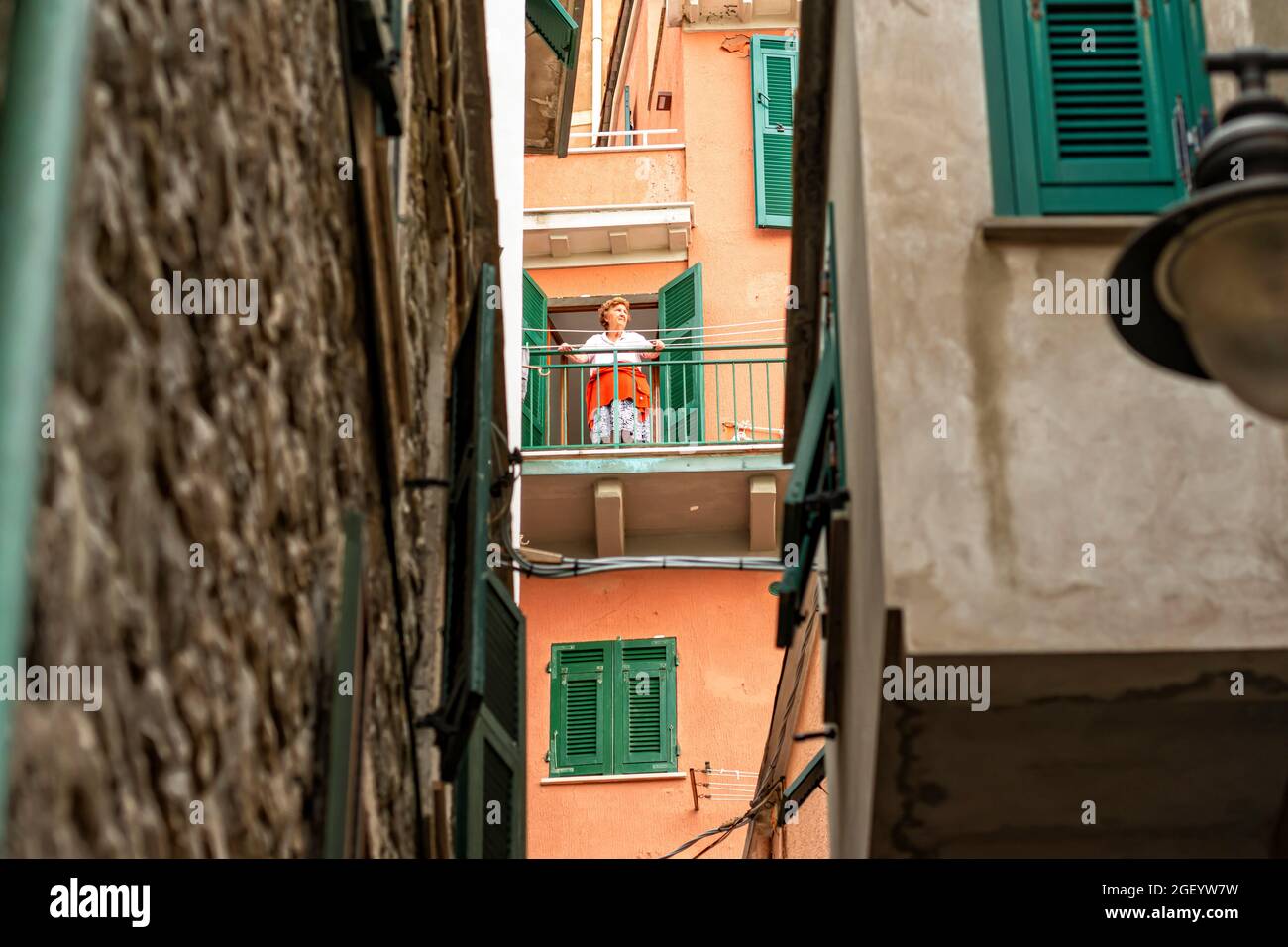 Manarola, Italy - August 10, 2021: woman on the bakona of a colorful ...