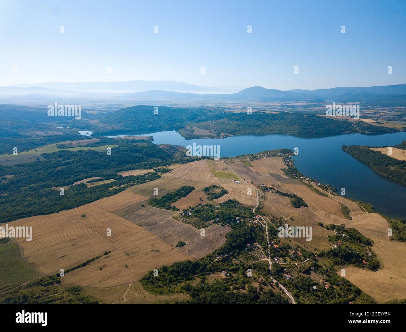 An aerial view of a blue lake, agricultural fields and mountains under ...