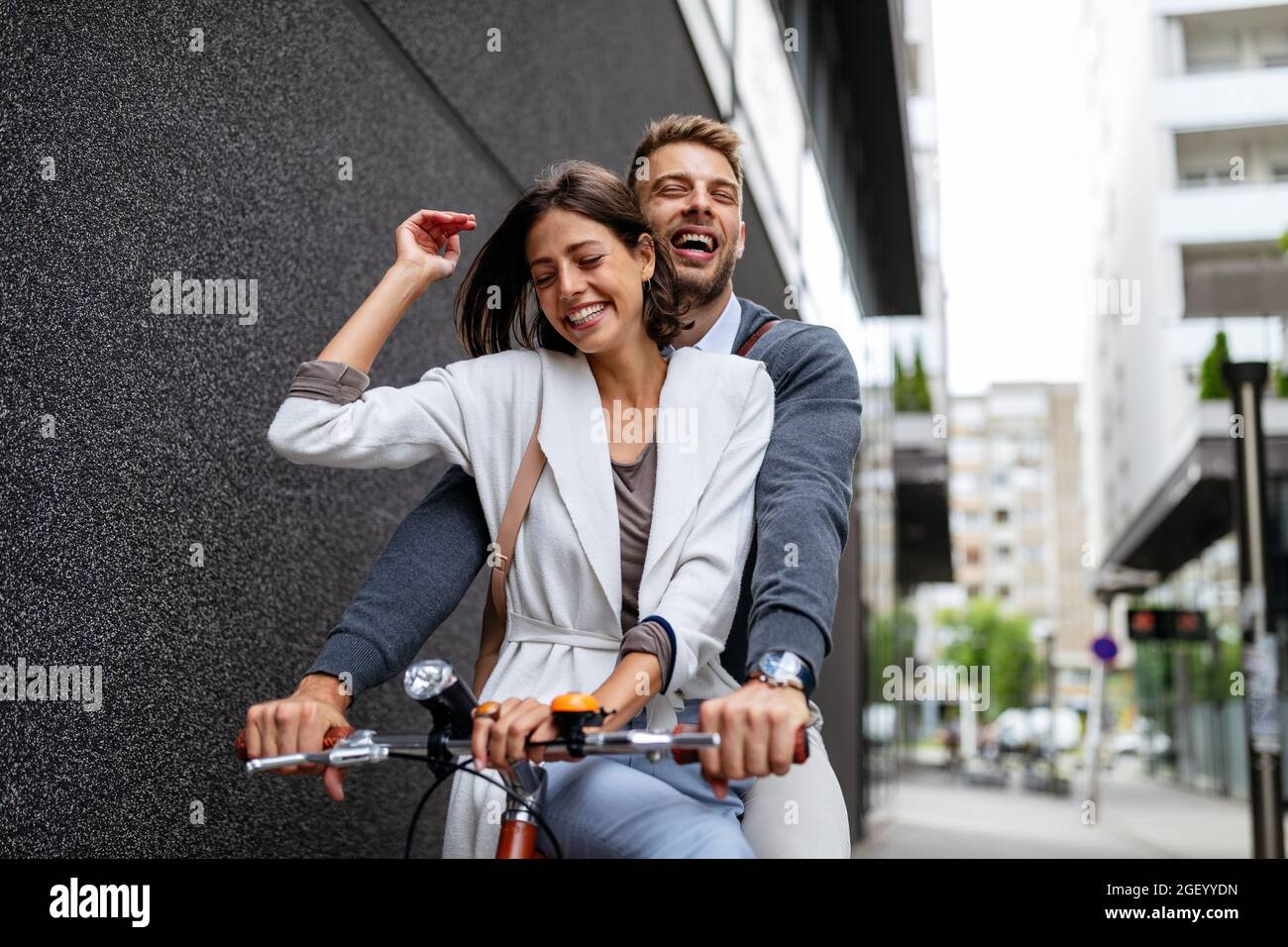Portrait of happy young couple riding a bike and having fun together ...