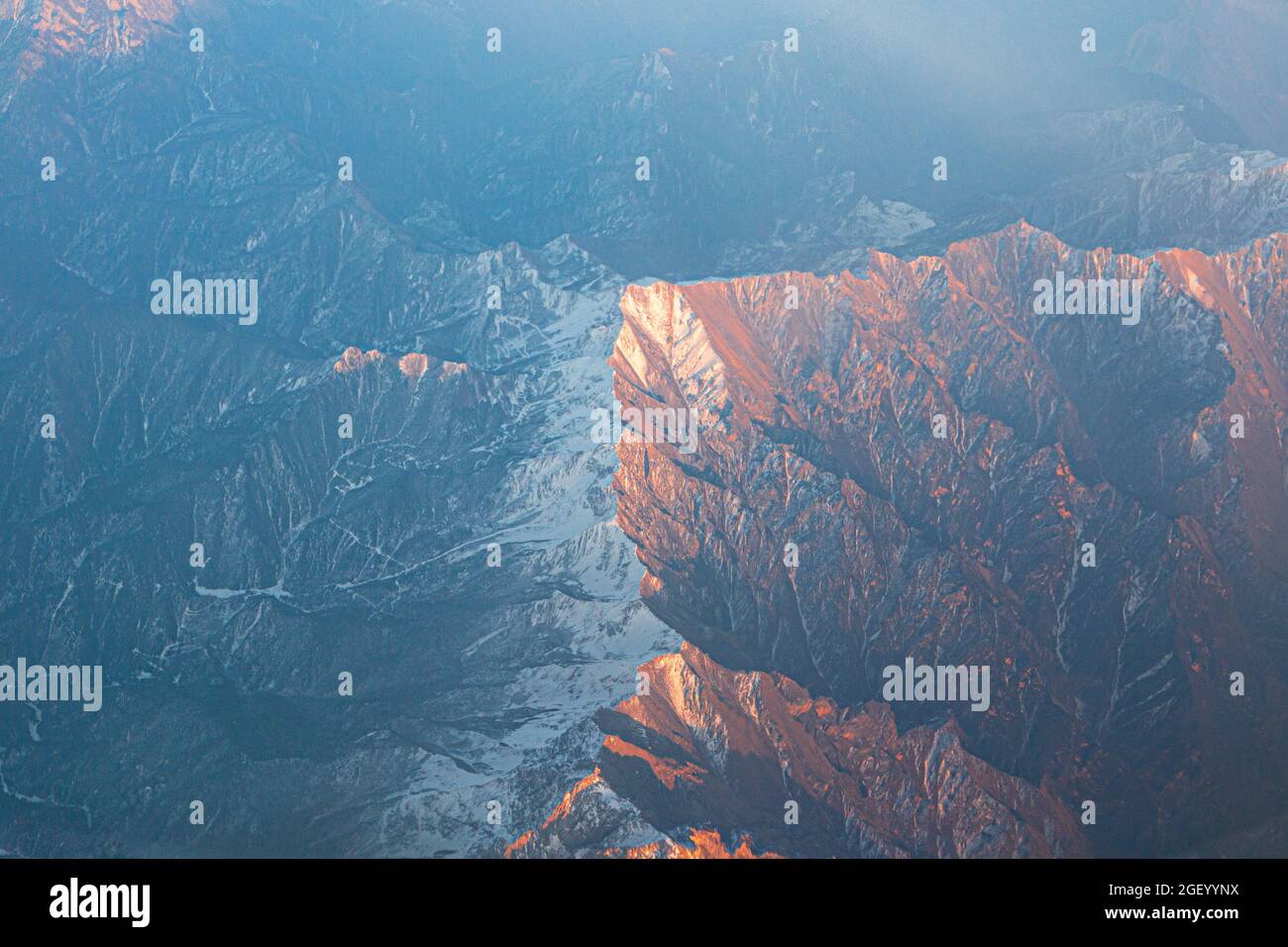 high mountain ranges illuminated by the sun, view from an airplane ...