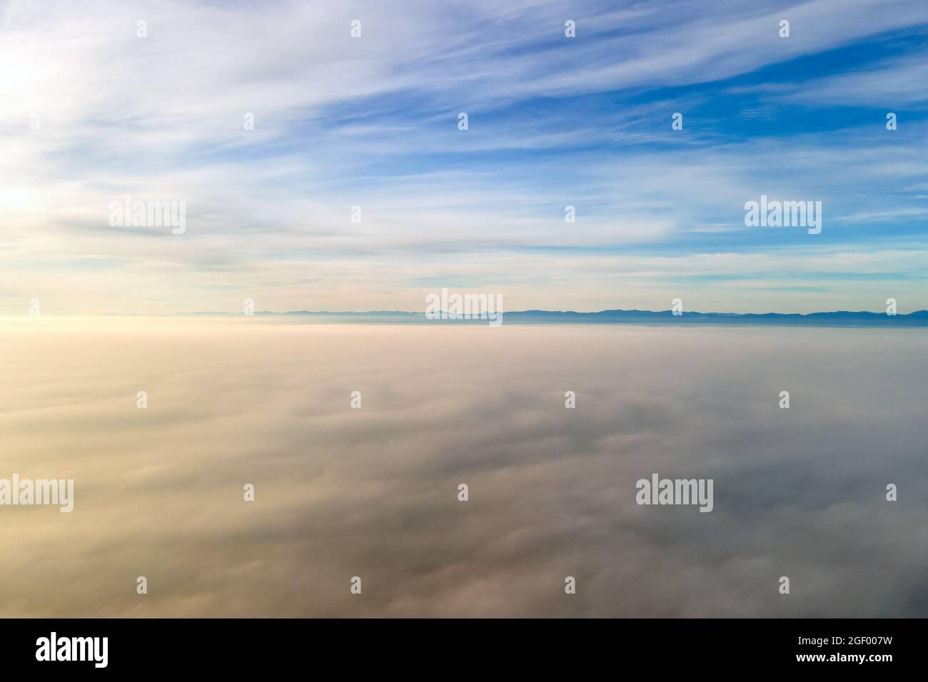 Aerial view of bright yellow sunset over white dense clouds with blue ...