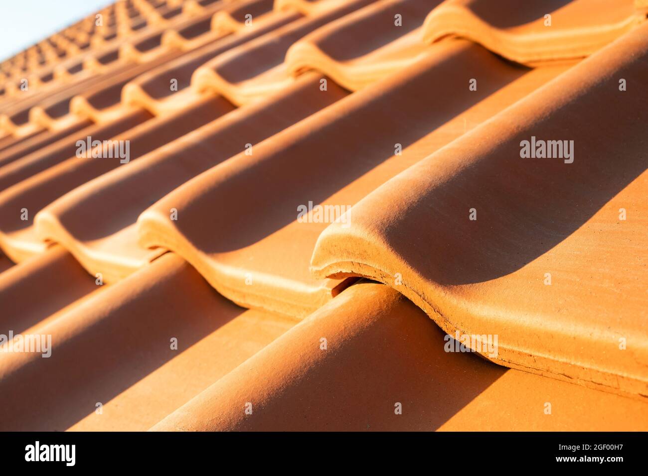Overlapping rows of yellow ceramic roofing tiles covering residential ...