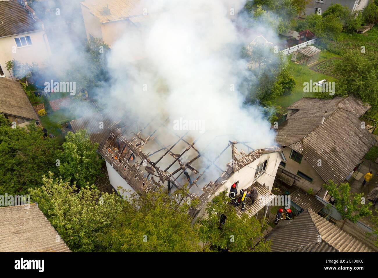 Aerial view of a house on fire with orange flames and white thick smoke ...