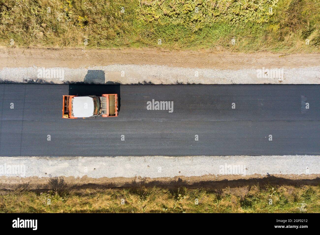 Aerial view of new road construction with steam roller machine at work ...
