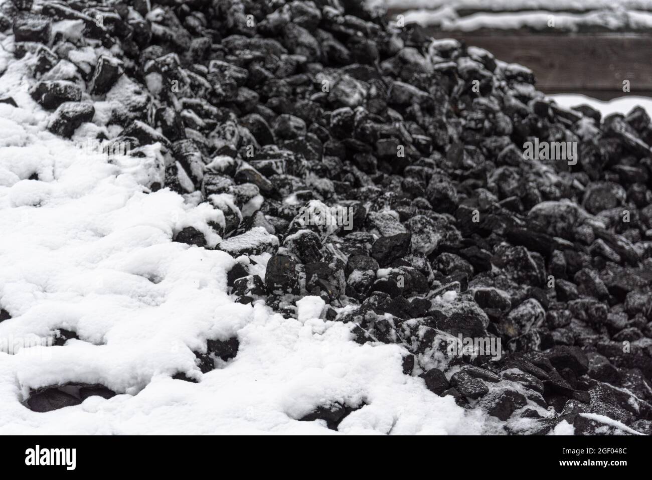 Coal covered with snow. Winter weather, fuel for heating homes. Storage ...