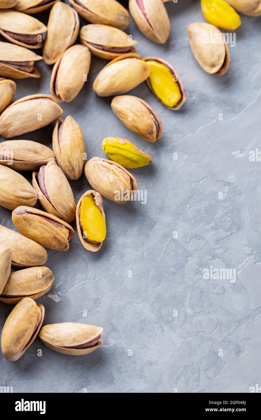 Pistachios nuts on a gray background. Roasted salted pistachios in shell. Concept of healthy ...