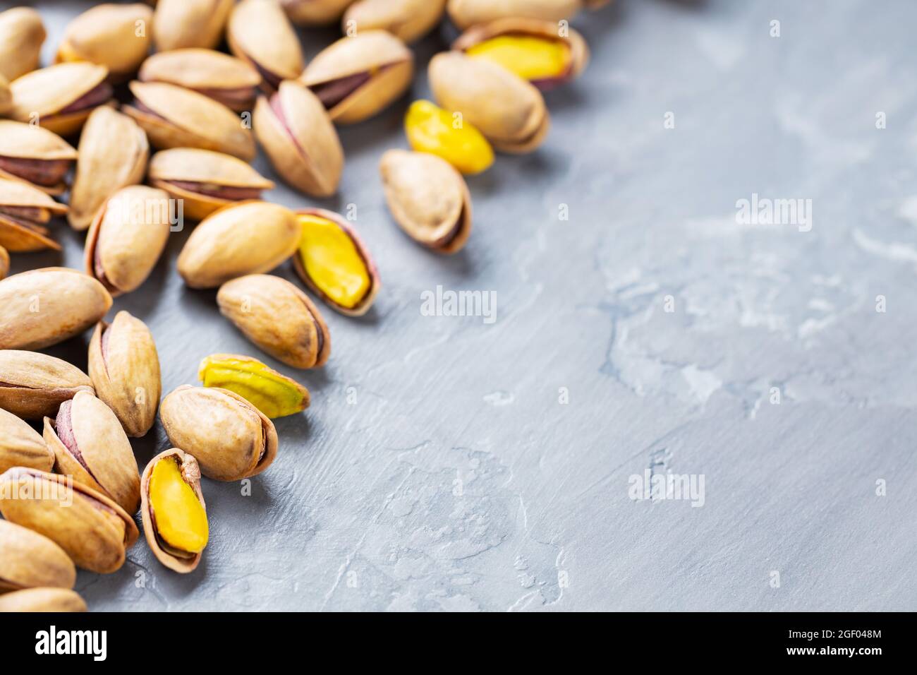 Pistachios nuts on a gray background. Roasted salted pistachios in shell. Concept of healthy ...