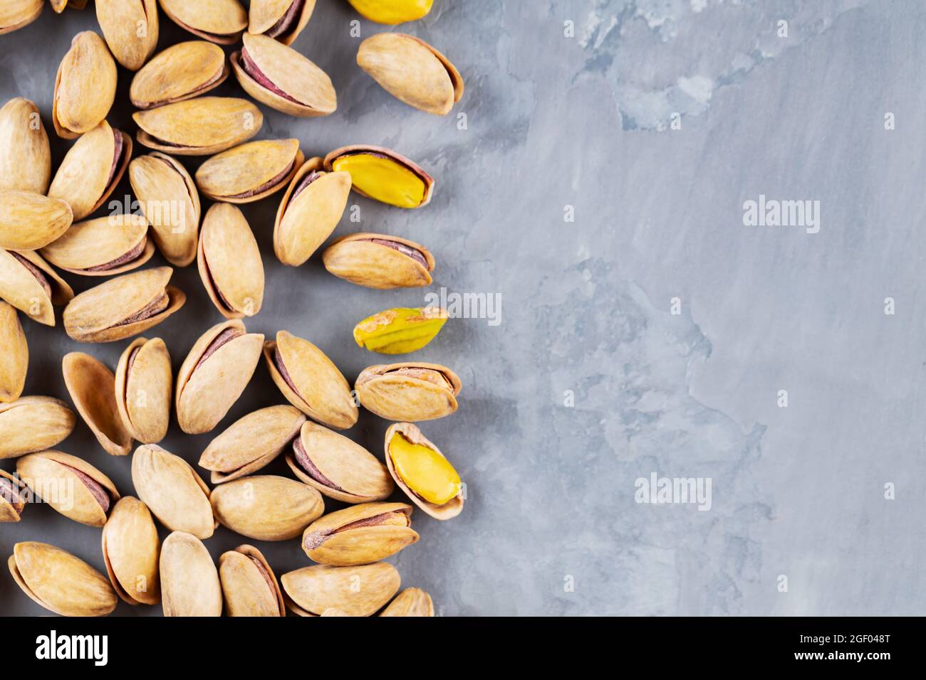 Pistachios nuts on a gray background. Roasted salted pistachios in shell. Concept of healthy ...